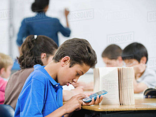 Student texting in classroom - Royalty-free Stock Photo | Dissolve