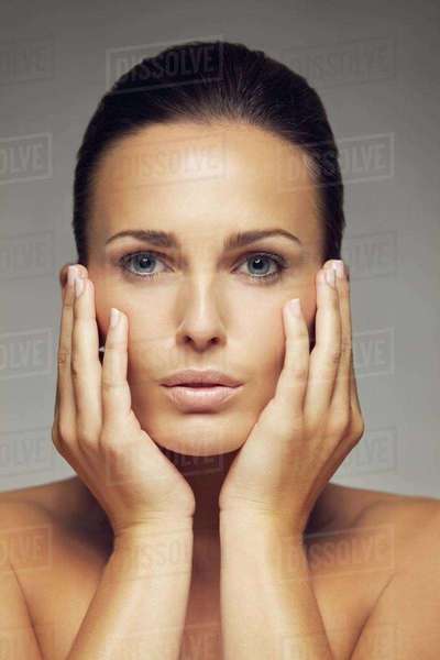 Closeup Portrait Of A Beautiful Young Brunette Gently Touching Her Face