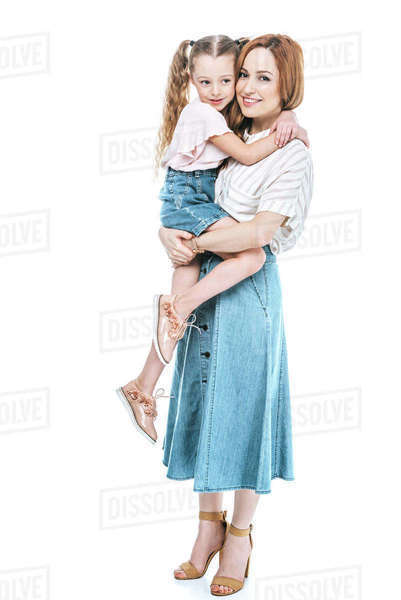 Happy mother carrying adorable little daughter and smiling at camera isolated on white - Stock ...