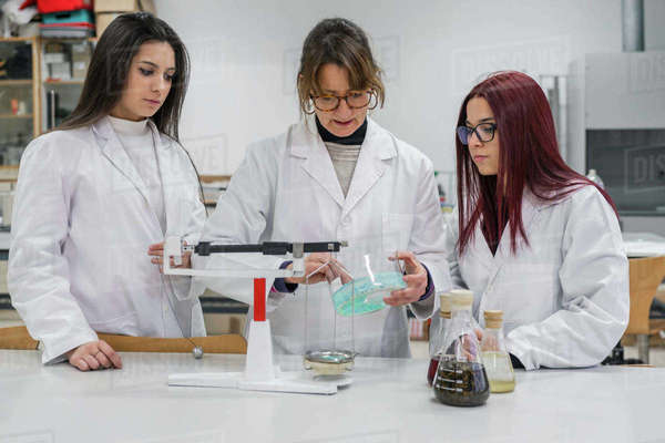 Female teacher and students conducting chemical experiment - Stock ...