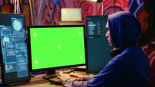 Asian Hacker In Hidden Place With Graffiti Walls Using Green Screen Computer To Deploy Malware