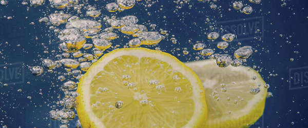 Underwater lemon slice in soda water or lemonade with bubbles. Refreshing soda tonic fizzy ...
