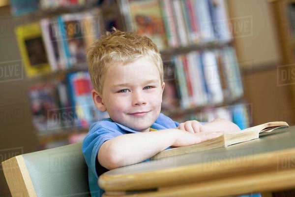 Boy Reading Book In Library - Royalty-free Stock Photo | Dissolve