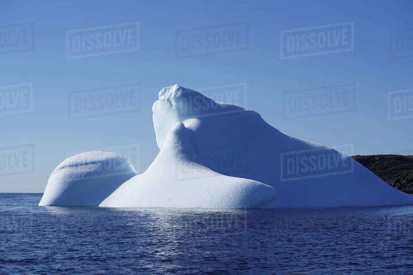 Pinnacle iceberg along a coast under a blue sky - Stock Photo - Dissolve