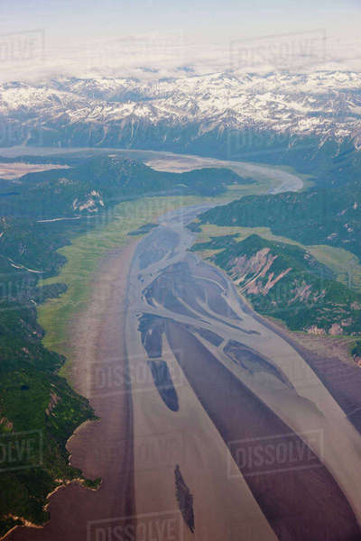 Aerial view of snow-capped peaks surrounding a green river valley ...
