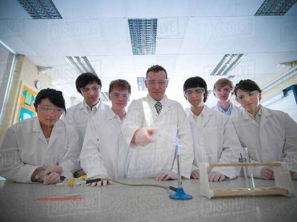 Science teacher and students conducting experiment in school laboratory ...