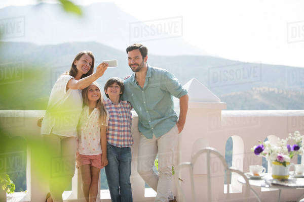 Family taking self-portrait on sunny balcony - Stock Photo - Dissolve
