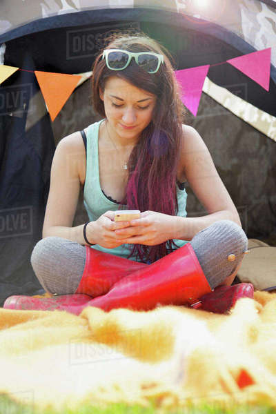 Teenage Girl Sitting Outside Tent Using Cell Phone - Stock Photo - Dissolve