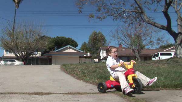 A girl loses her footing on a plastic tricycle and rolls down a ...