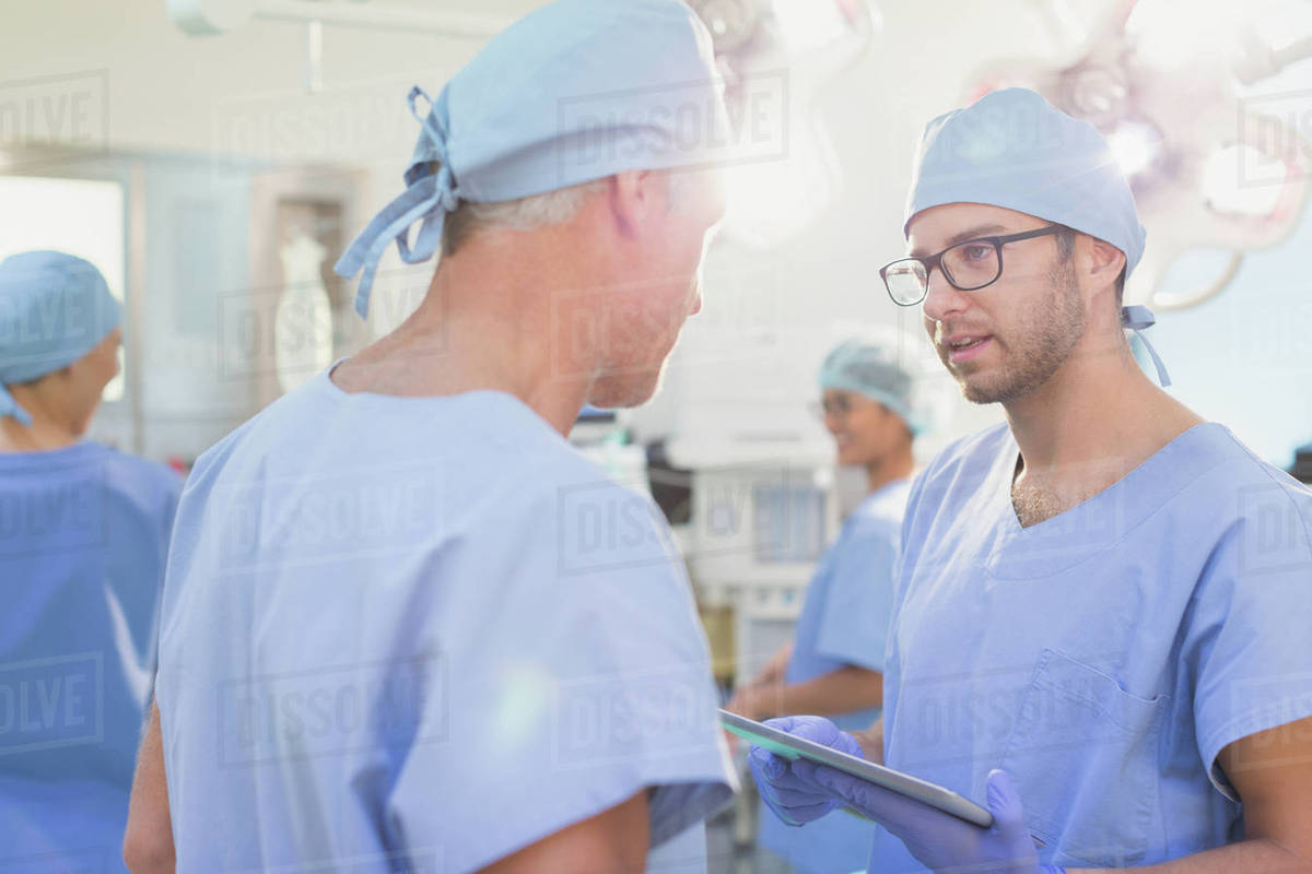 Male surgeons with digital tablet talking in operating room - Royalty ...