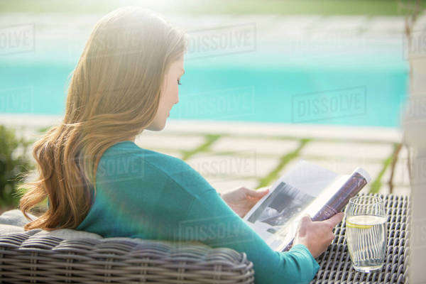 Brunette woman reading magazine at luxury poolside - Royalty-free Stock ...