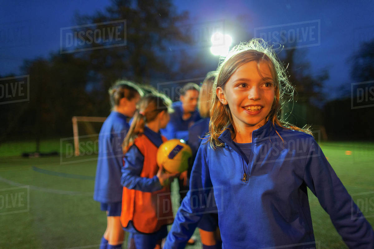 Smiling girl playing soccer on field at night - Royalty-free Stock ...