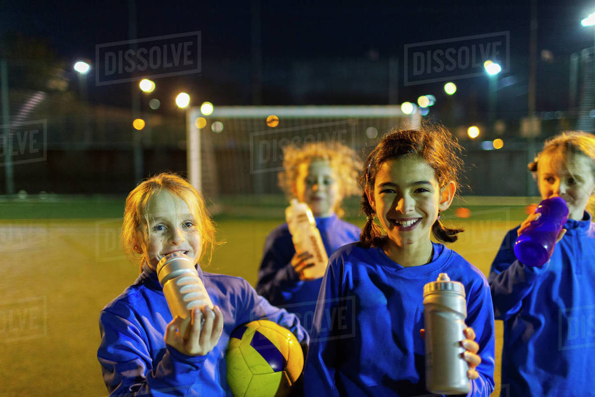 Portrait smiling girls soccer team taking a break from practice ...