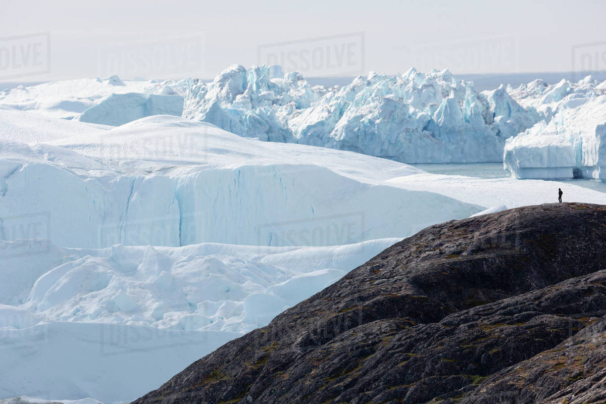 Man on cliff overlooking majestic polar glaciers Greenland - Stock ...