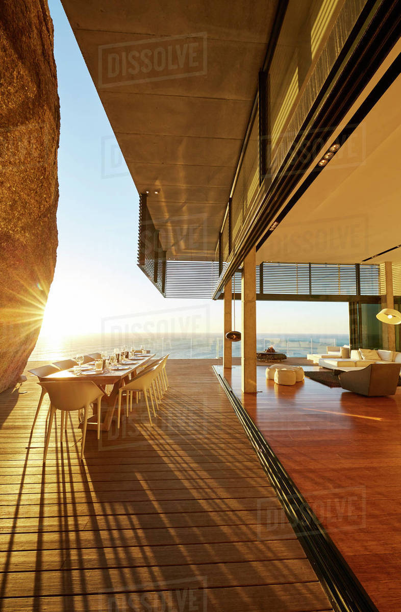 Dining table on modern luxury patio with sunset ocean view - Royalty ...