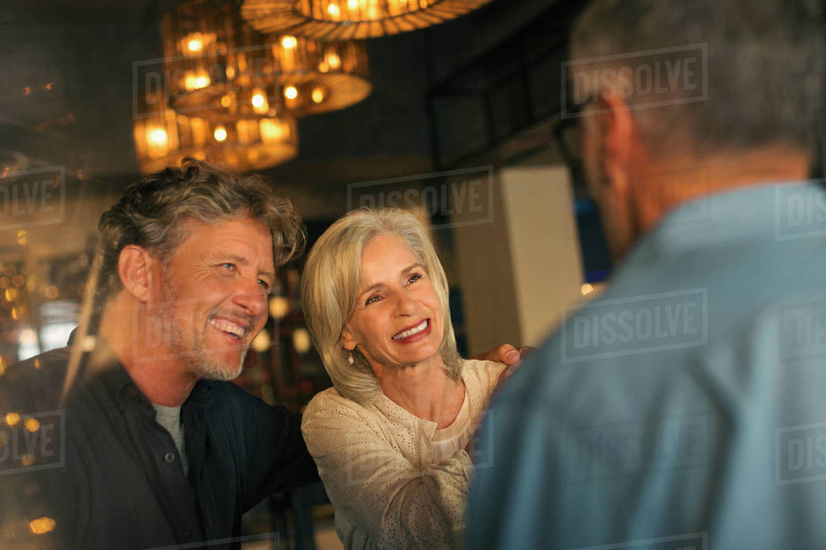 Smiling friends talking in restaurant - Royalty-free Stock Photo | Dissolve