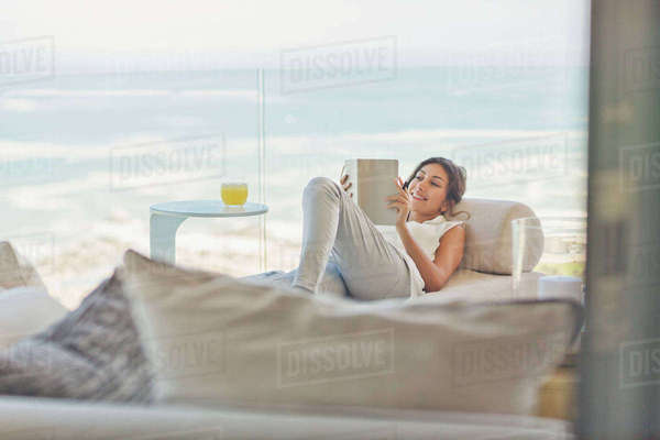 Woman relaxing reading book on chaise lounge on luxury balcony with ...