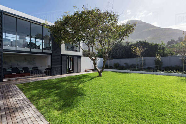 Sunny home showcase exterior lawn and tree below mountain - Stock Photo ...