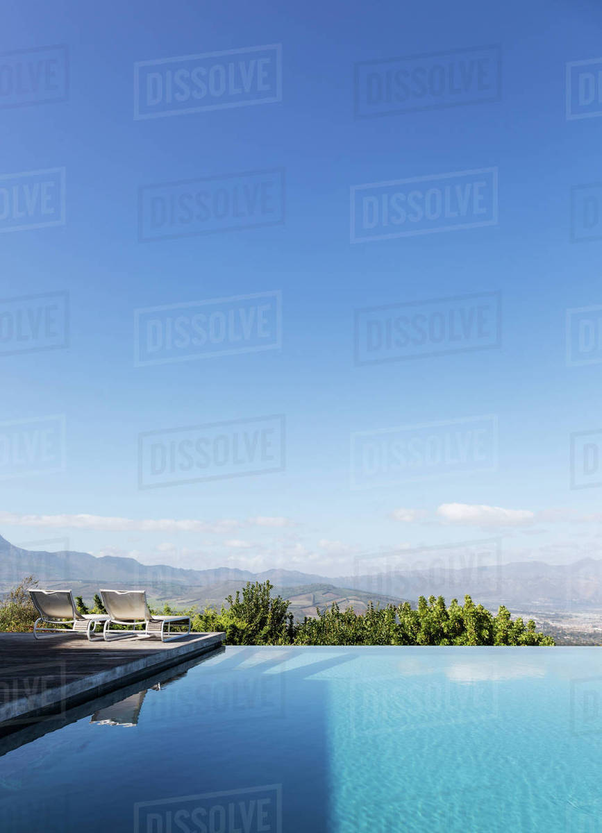 Tranquil luxury infinity pool with mountain view below sunny blue sky ...