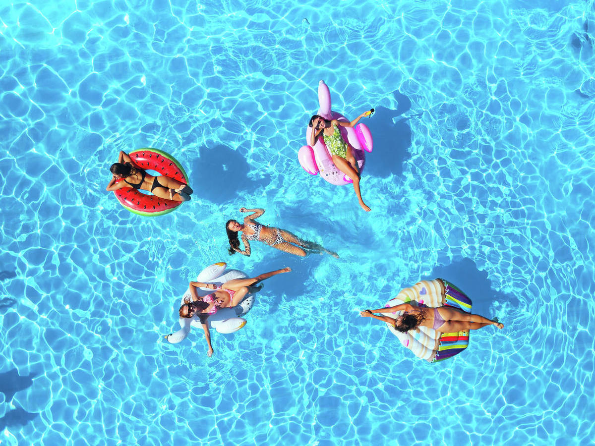 Aerial. Hot pretty girls in bikini swimming in pool on floaties. Top ...