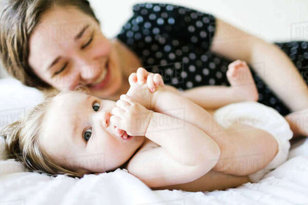 Baby girl biting foot - Stock Photo - Dissolve
