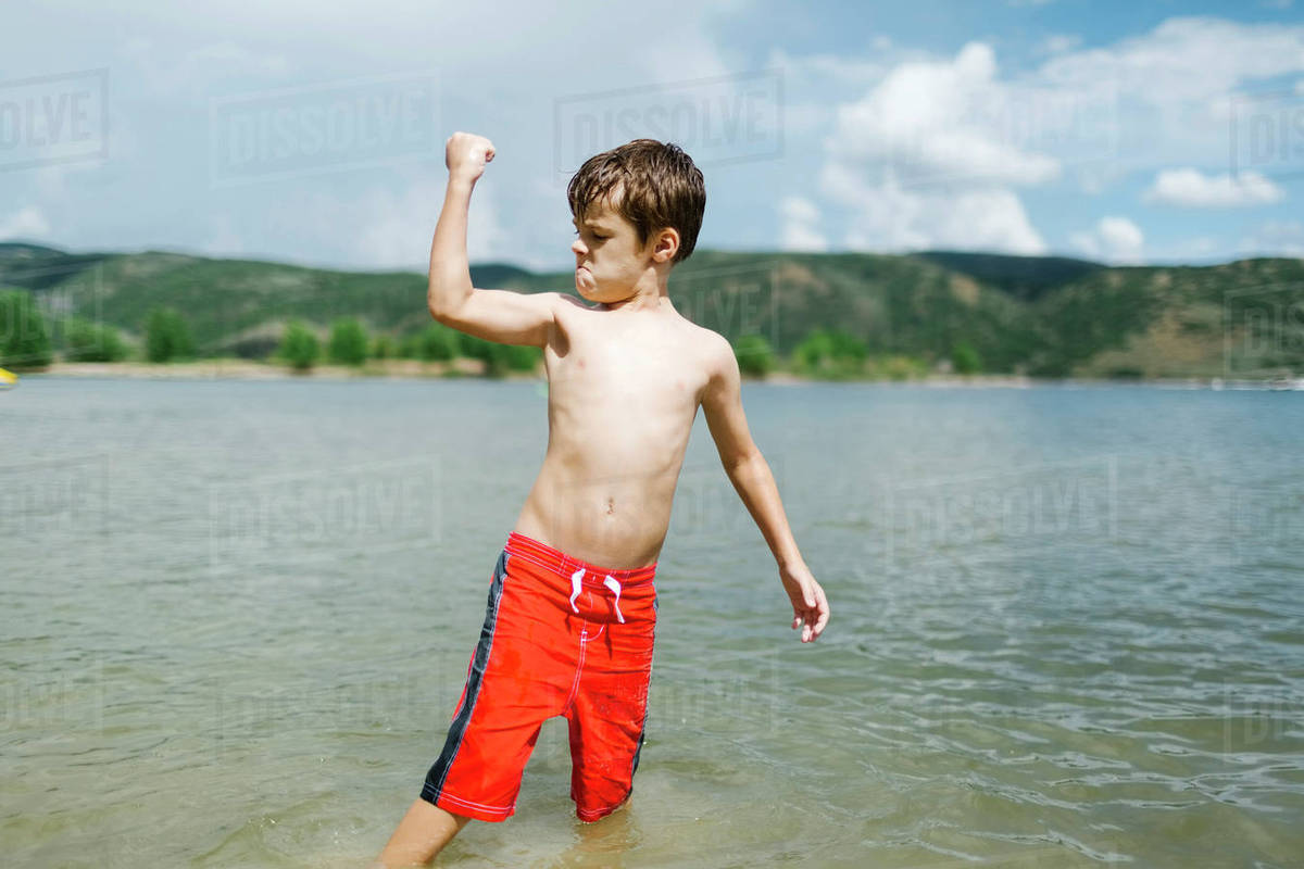 USA, Utah, Park City, Boy flexing muscles while wading in lake ...