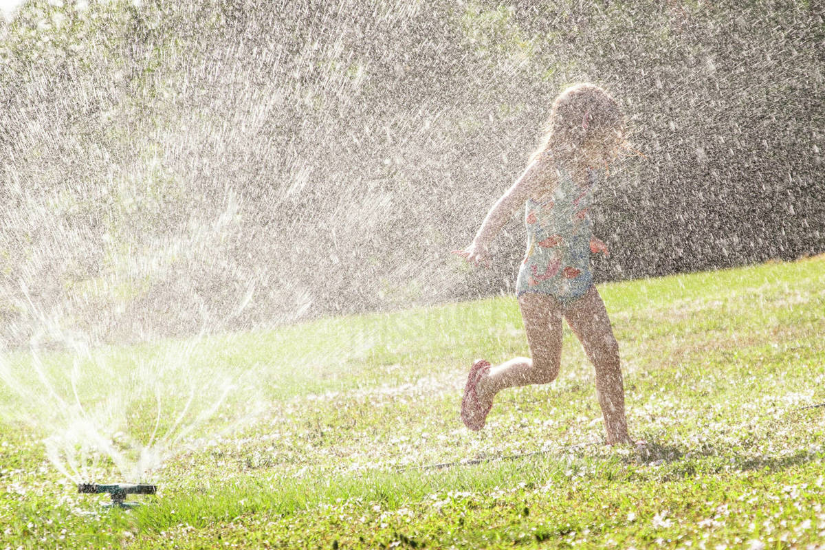 Girl splashing in sprinkler water on lawn - Royalty-free Stock Photo ...