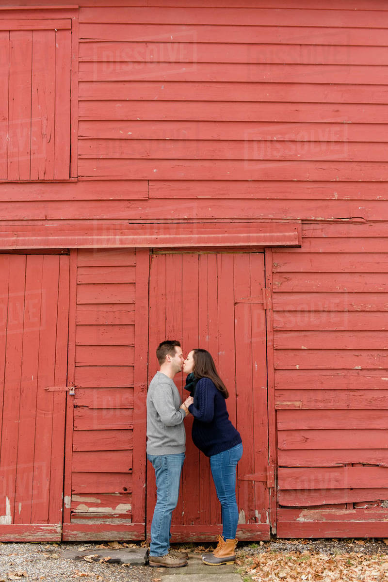 Couple kissing in front of red barn - Royalty-free Stock Photo | Dissolve