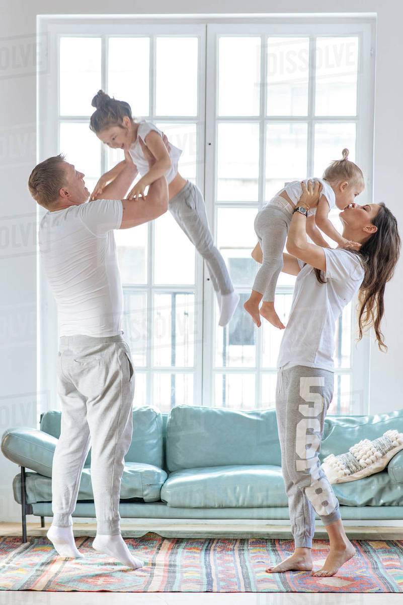 Parent lifting daughters by window - Stock Photo - Dissolve