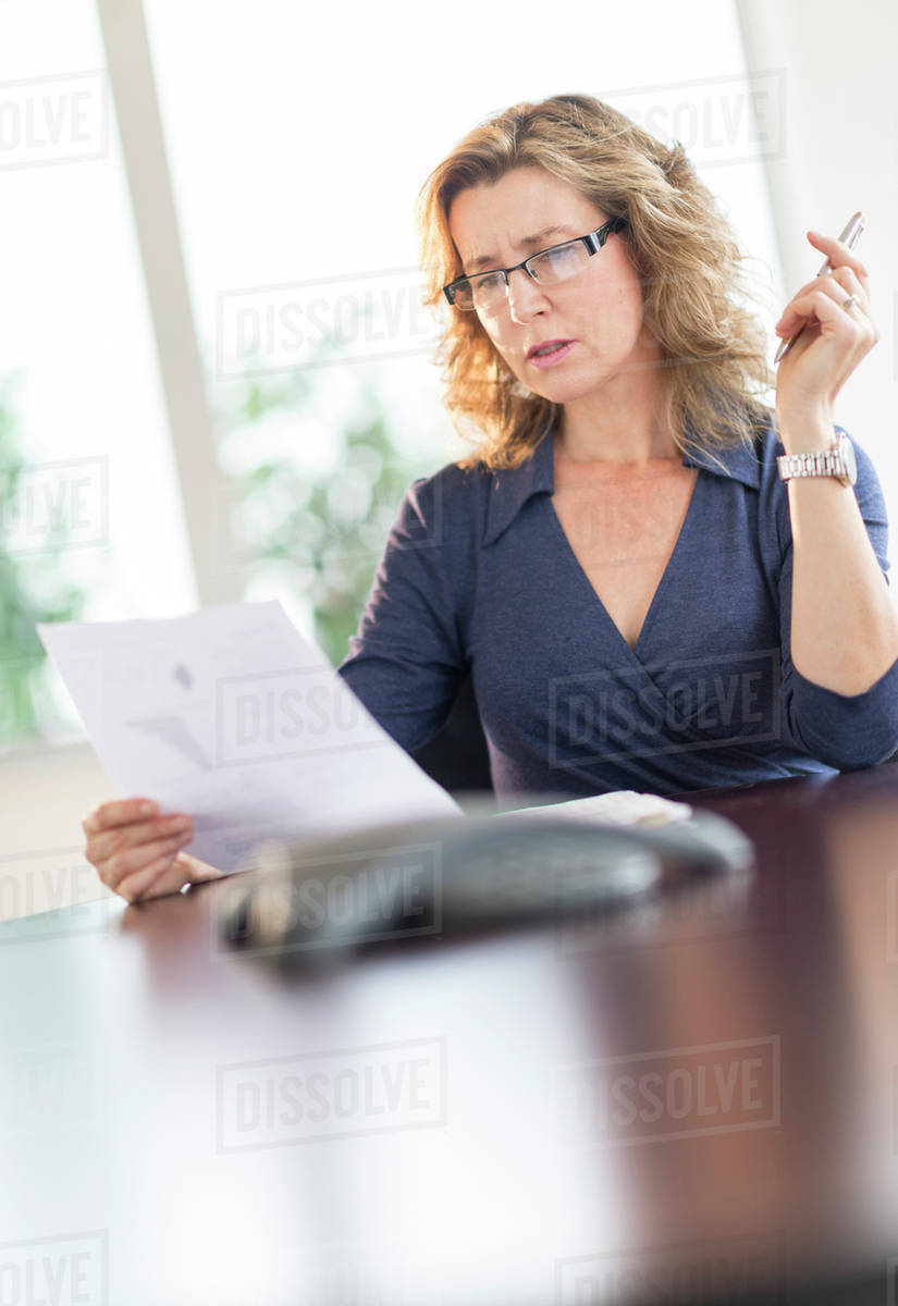 Business woman reading document - Stock Photo - Dissolve