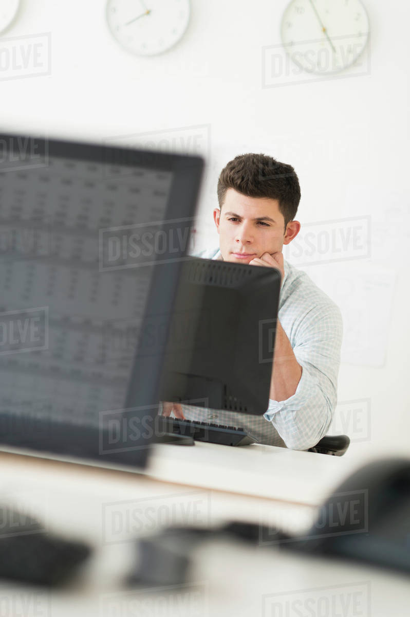 Young man sitting in front of desk and working - Royalty-free Stock ...