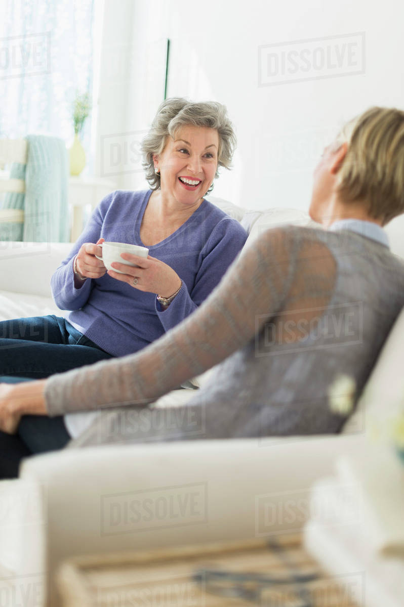 Two women sitting on coach talking - Royalty-free Stock Photo | Dissolve