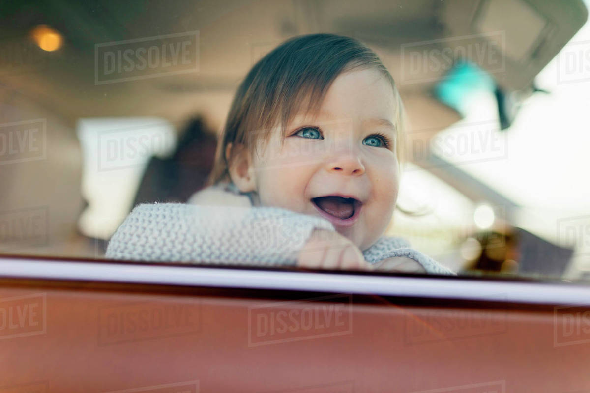 Smiling baby girl behind car window - Stock Photo - Dissolve