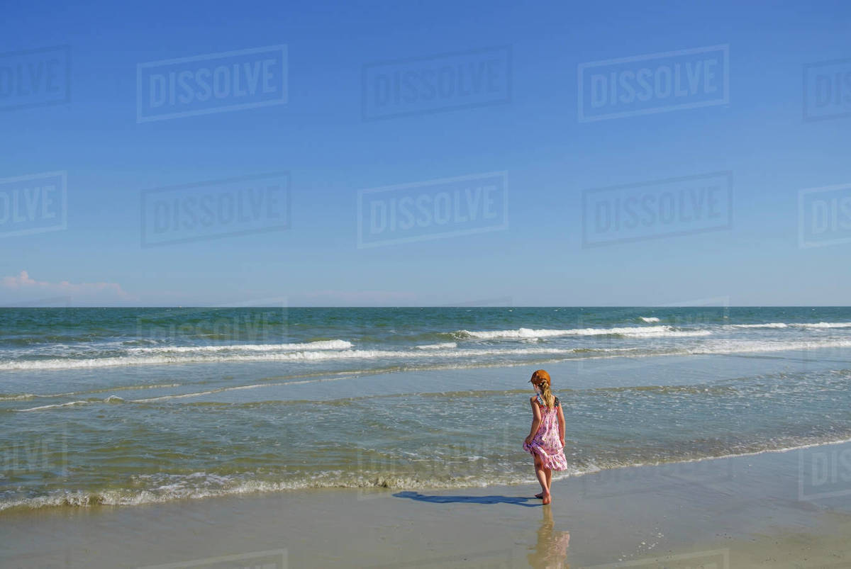 Rear view of girl walking on beach - Royalty-free Stock Photo | Dissolve