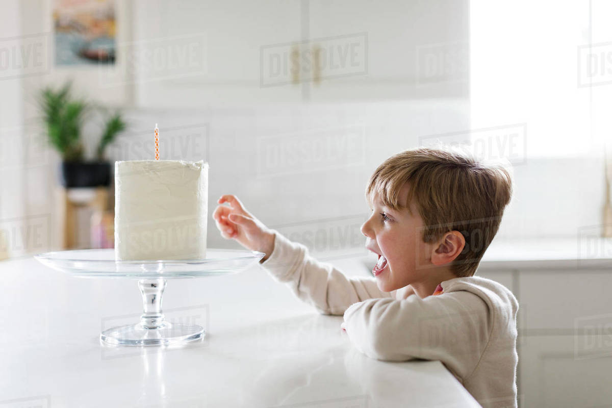 Boy reaching for birthday cake - Royalty-free Stock Photo | Dissolve