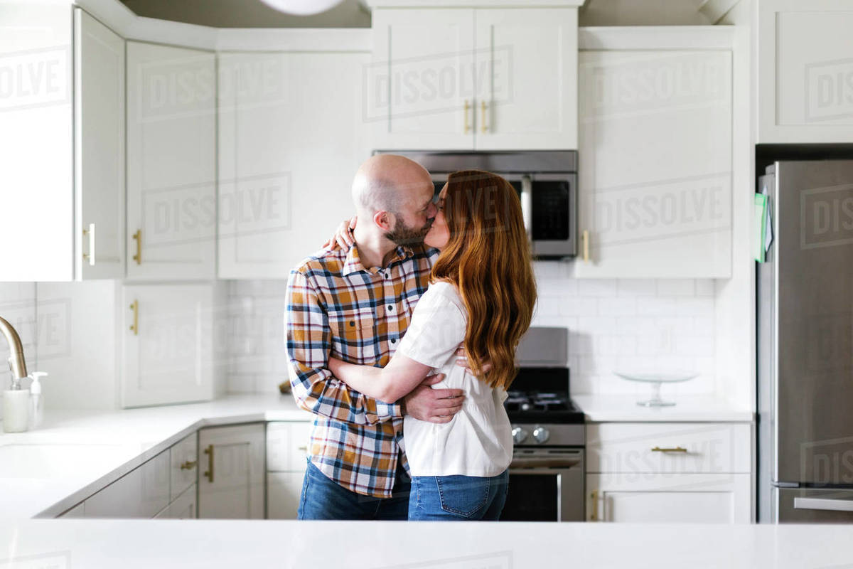 Couple kissing in kitchen - Stock Photo - Dissolve