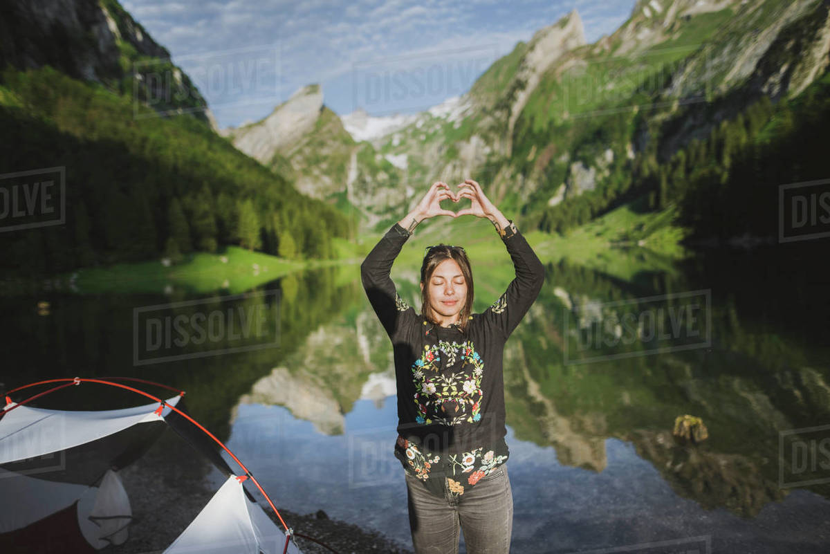 Woman making heart hand sign by Seealpsee lake in Appenzell Alps ...