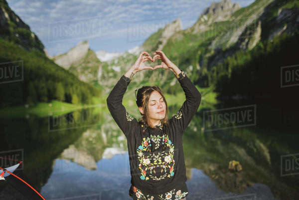 Woman making heart hand sign by Seealpsee lake in Appenzell Alps ...
