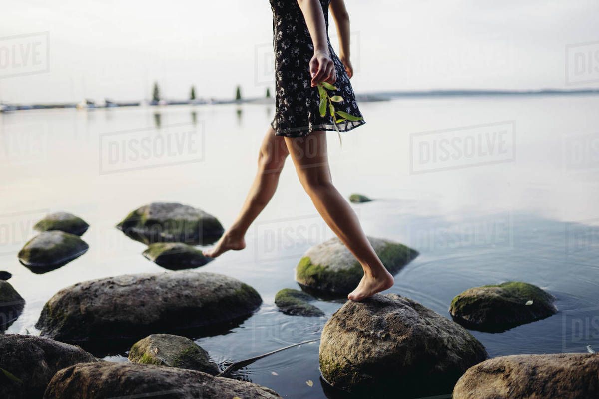 Barefoot woman stepping on rocks in sea - Royalty-free Stock Photo ...