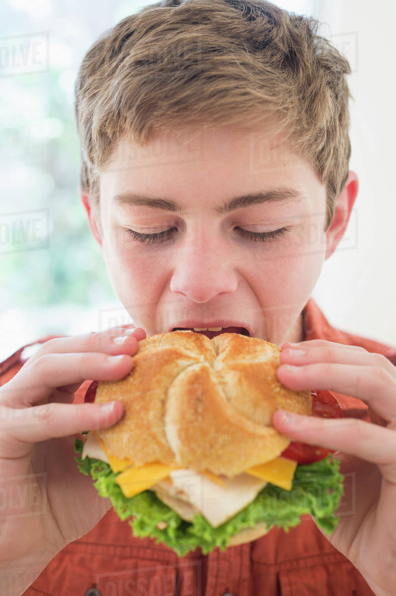 Teenage boy (16-17) eating cheese and turkey sandwich - Royalty-free ...