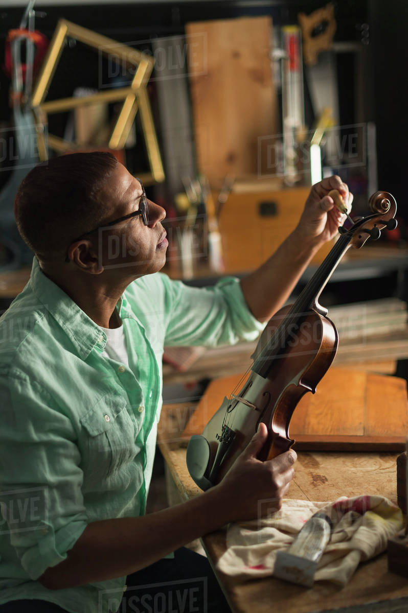 Mature man fixing violin in his workshop - Stock Photo - Dissolve
