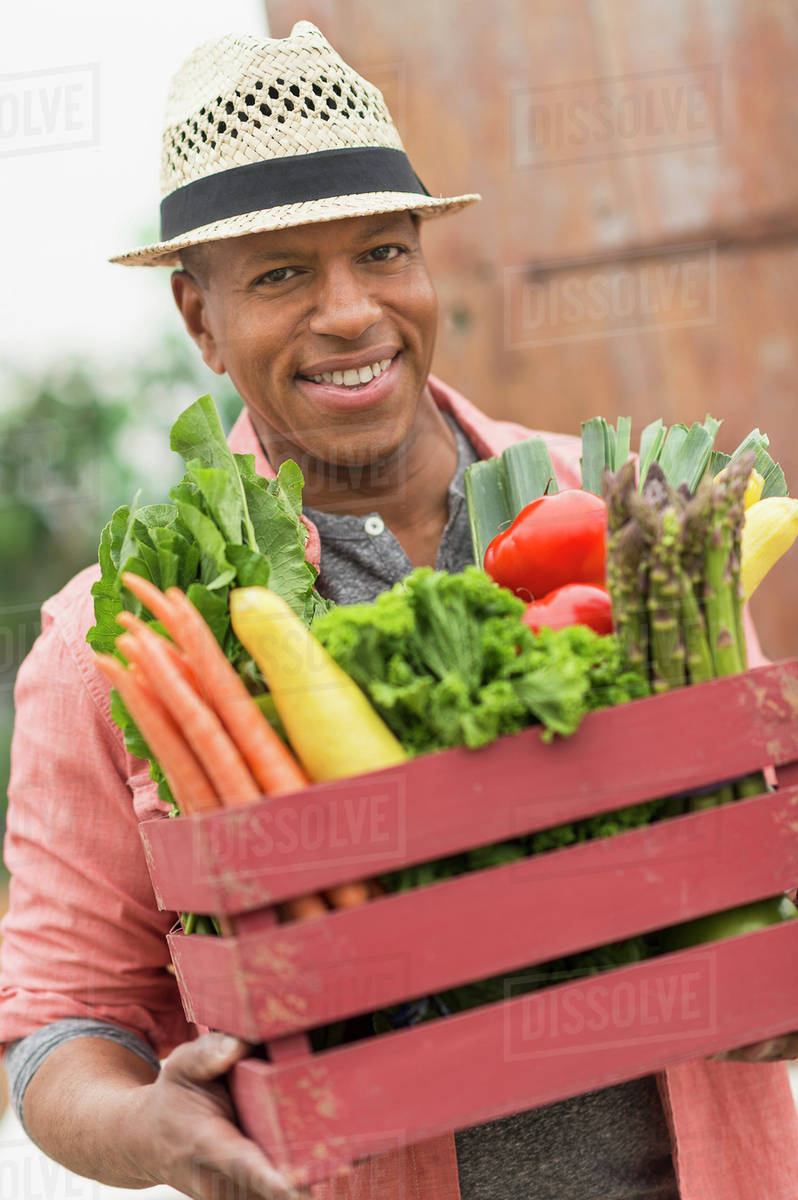 Portrait of man carrying crate full of fresh vegetables - Royalty-free ...