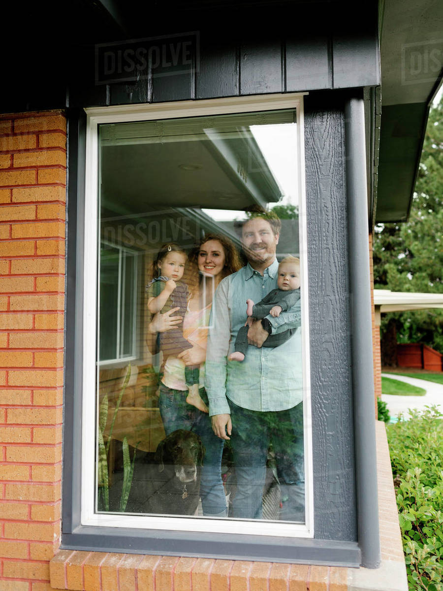 Family with small children looking through window - Stock Photo - Dissolve