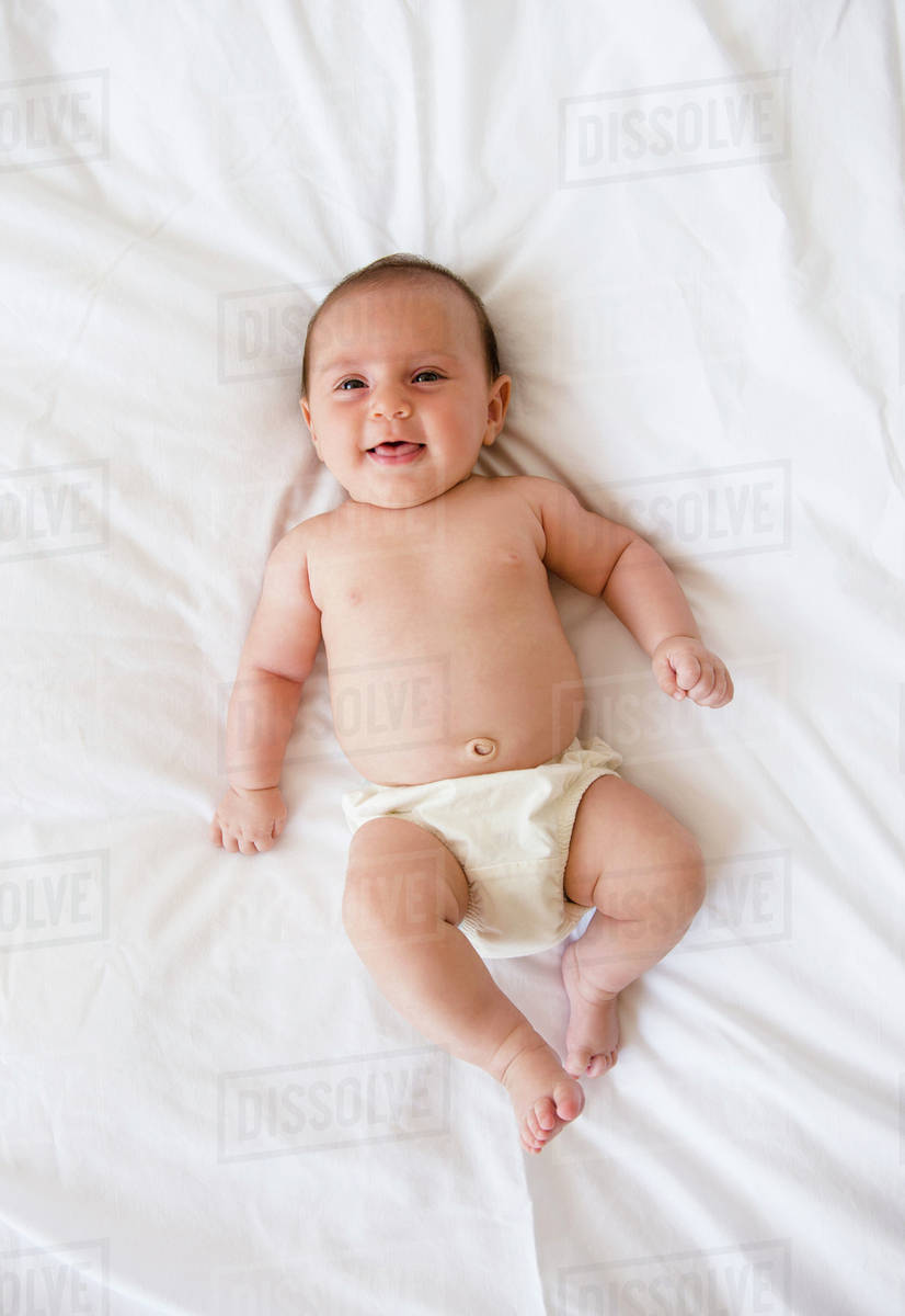 Baby girl (2-5 months) lying on bed - Royalty-free Stock Photo | Dissolve