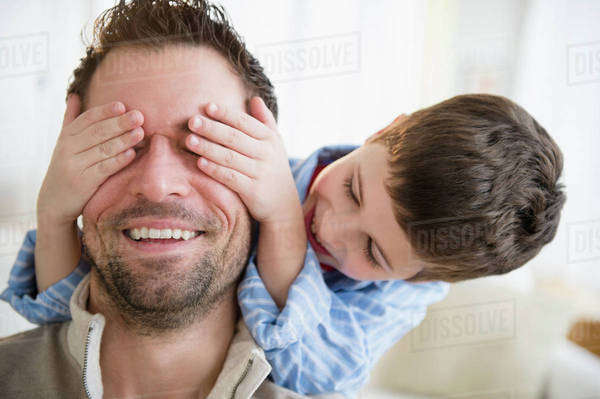 Son (8-9) covering father's eyes - Royalty-free Stock Photo | Dissolve