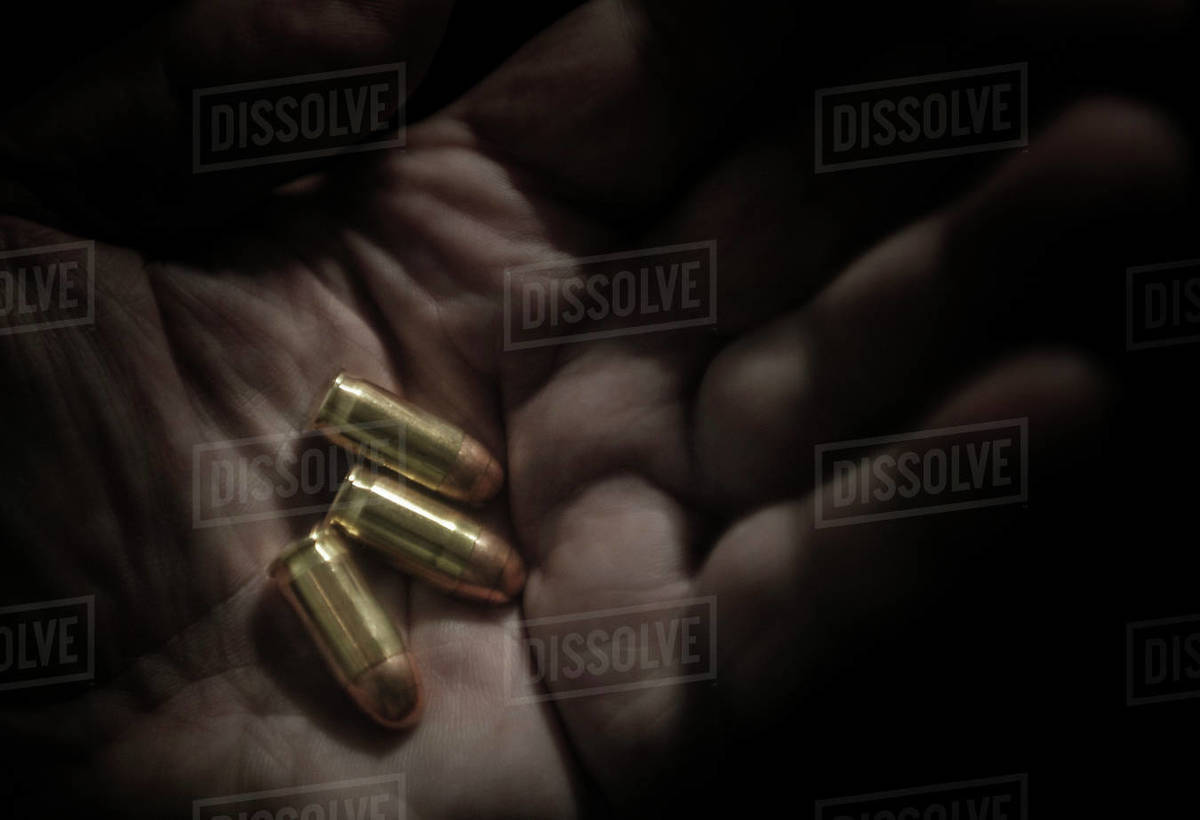 Close-up of hand holding bullets - Royalty-free Stock Photo | Dissolve