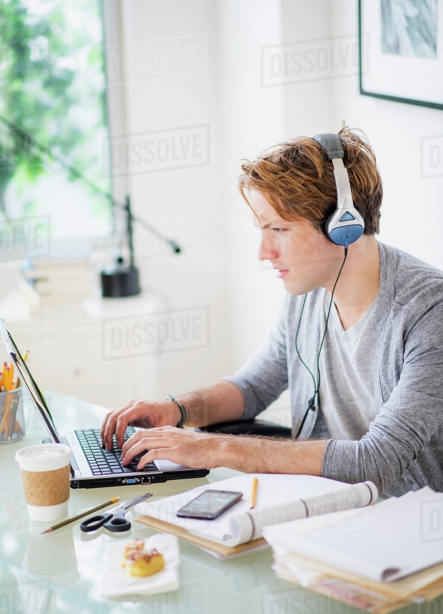 Man multi-tasking in home office - Stock Photo - Dissolve