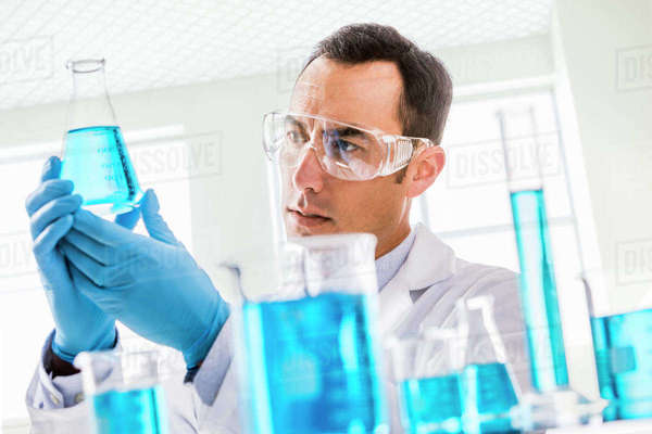 Scientist looking at blue liquid in laboratory - Royalty-free Stock ...