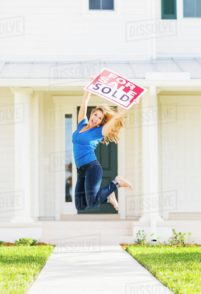 Woman jumping in front of new house - Royalty-free Stock Photo | Dissolve