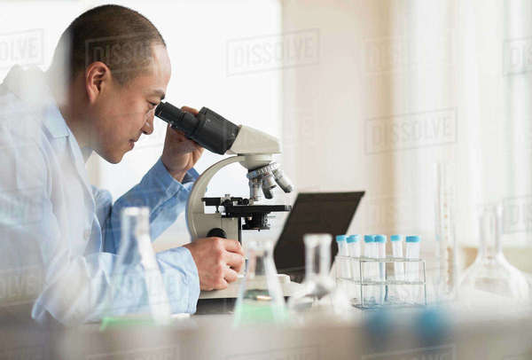 Korean scientist using microscope in laboratory - Stock Photo - Dissolve